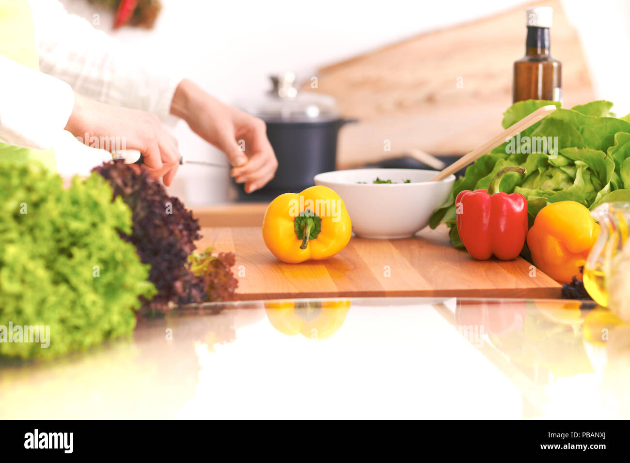 Close Up of human hands cooking vegetable salad in kitchen on the glass ...