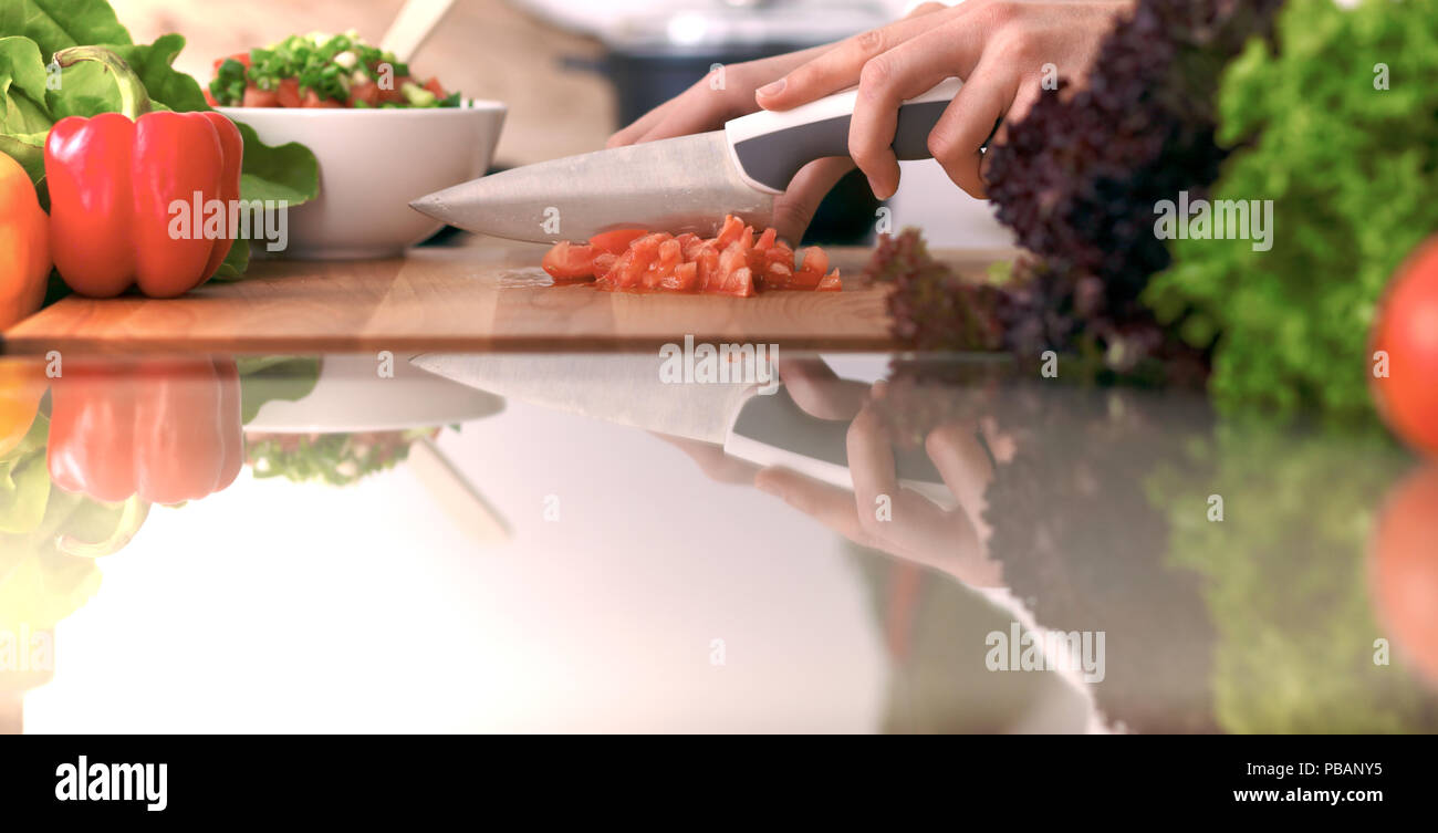 Close Up of human hands cooking vegetable salad in kitchen on the glass ...