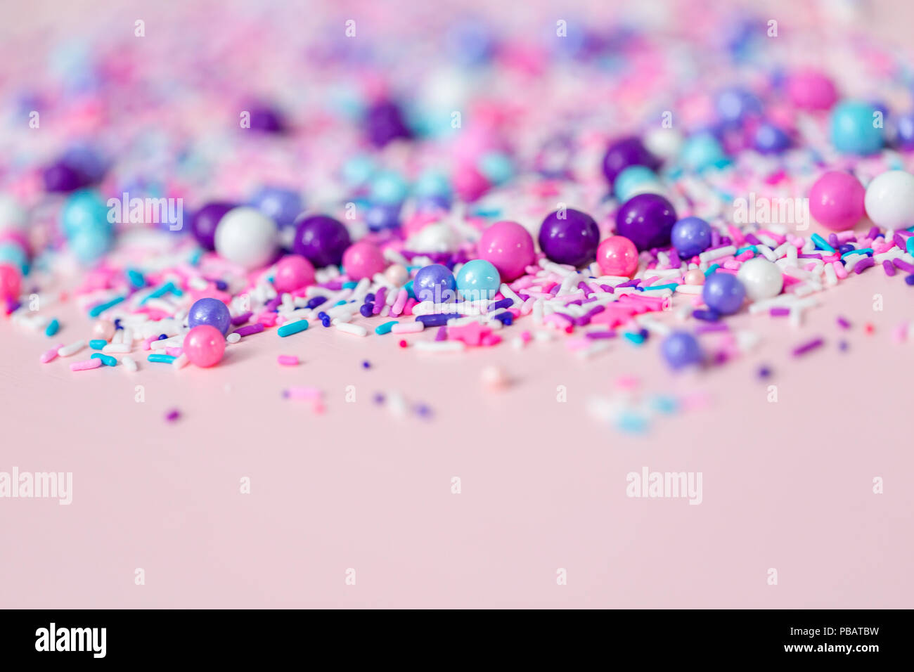 Colorful purple sprinkle blend on a pink background Stock Photo - Alamy