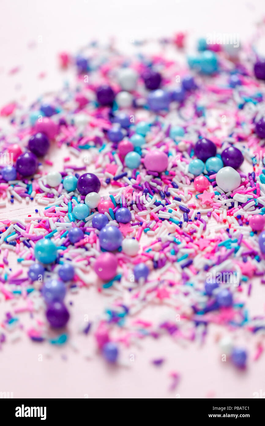 Colorful purple sprinkle blend on a pink background Stock Photo - Alamy