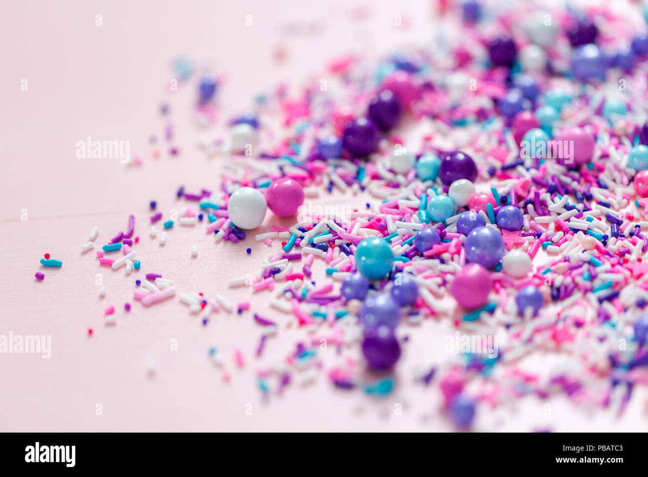 Colorful purple sprinkle blend on a pink background Stock Photo - Alamy