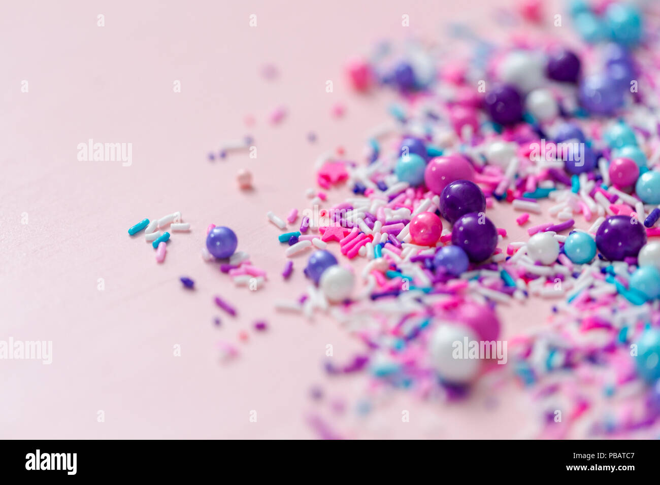 Colorful purple sprinkle blend on a pink background Stock Photo - Alamy