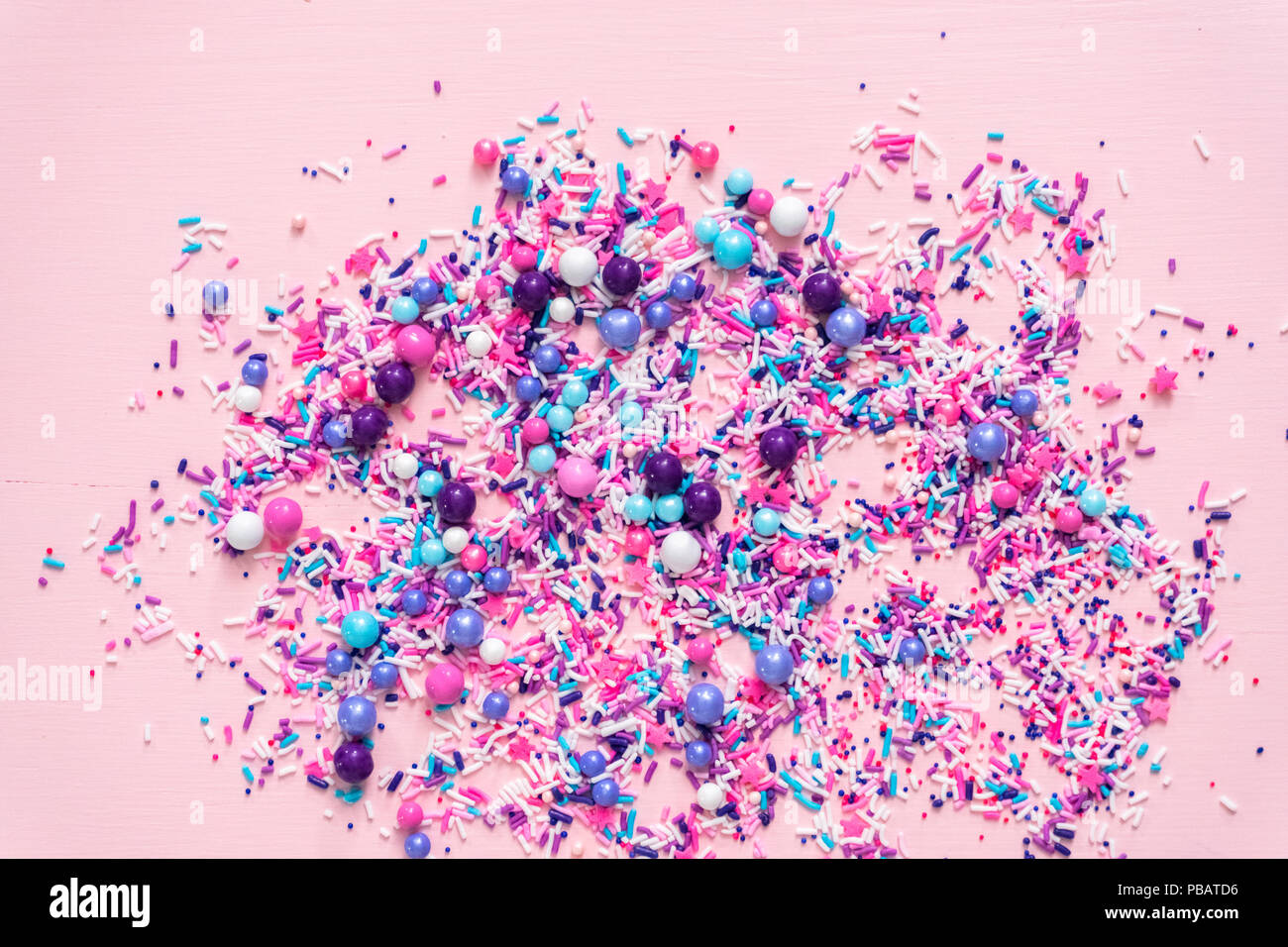 Colorful purple sprinkle blend on a pink background Stock Photo - Alamy