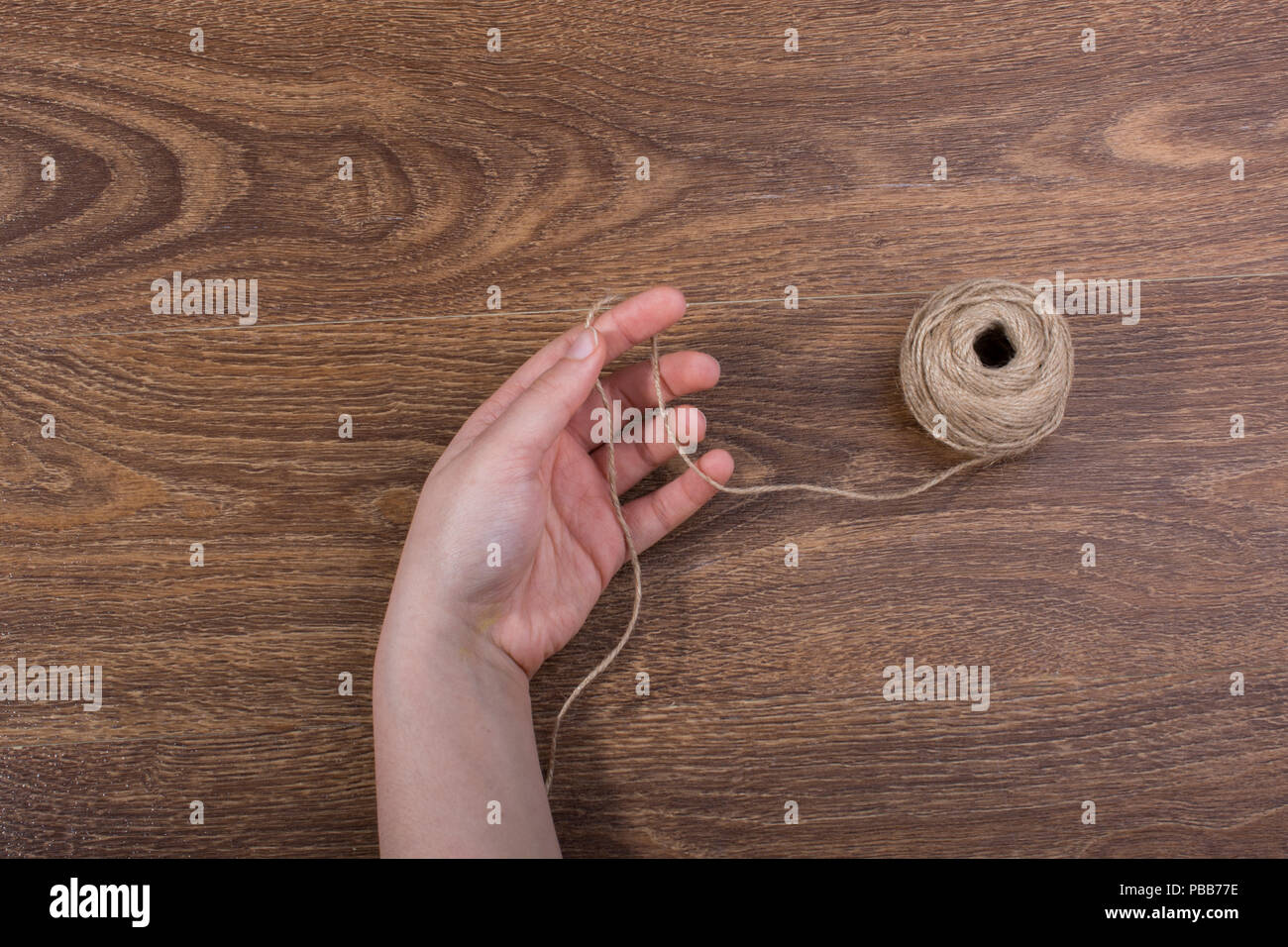 Spool of brown string in hand on brown background Stock Photo - Alamy