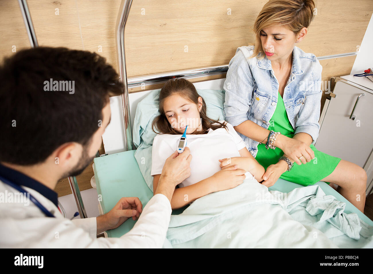 Doctor taking body temperature of her patient in hospital room Stock ...