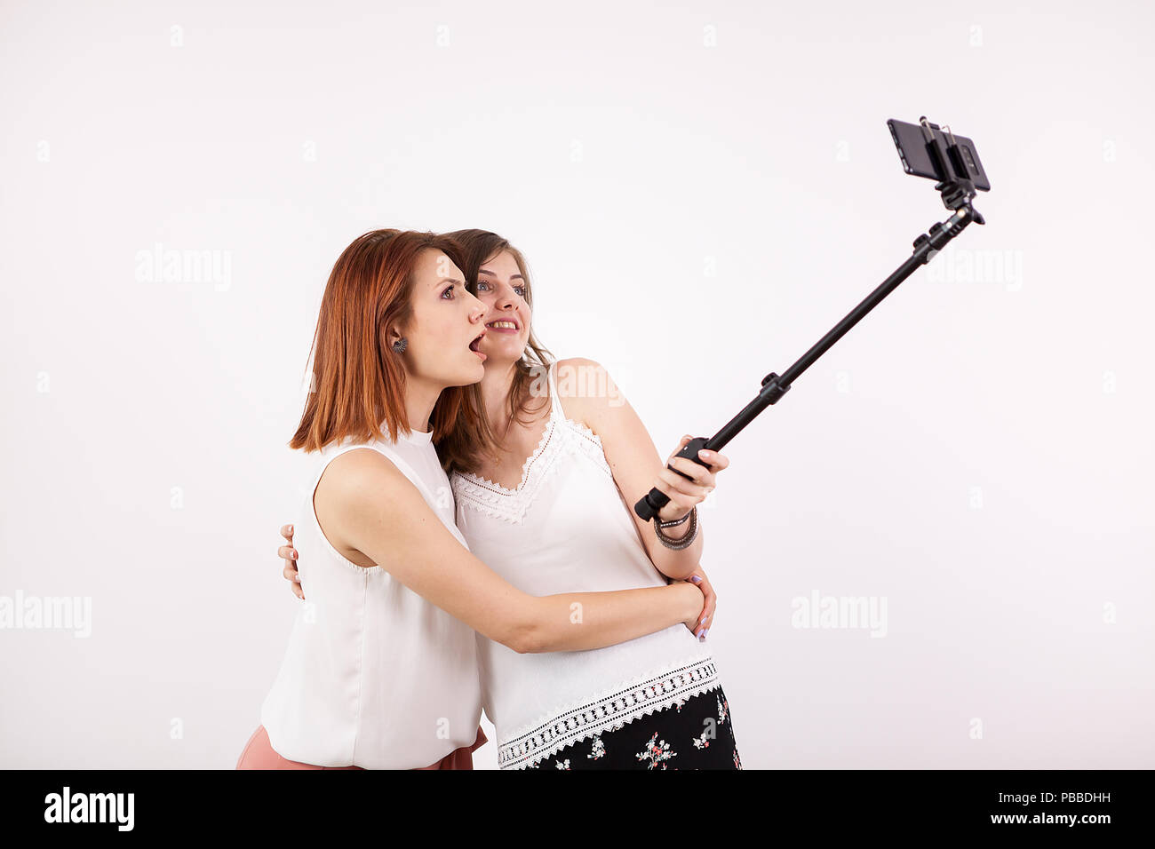 Portrait of two beautiful young woman taking a selfie with a selfie ...