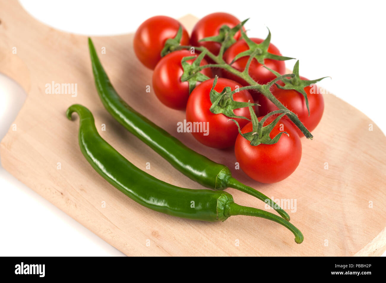 tomatoes and green peppers on the wooden cutting board, white ...