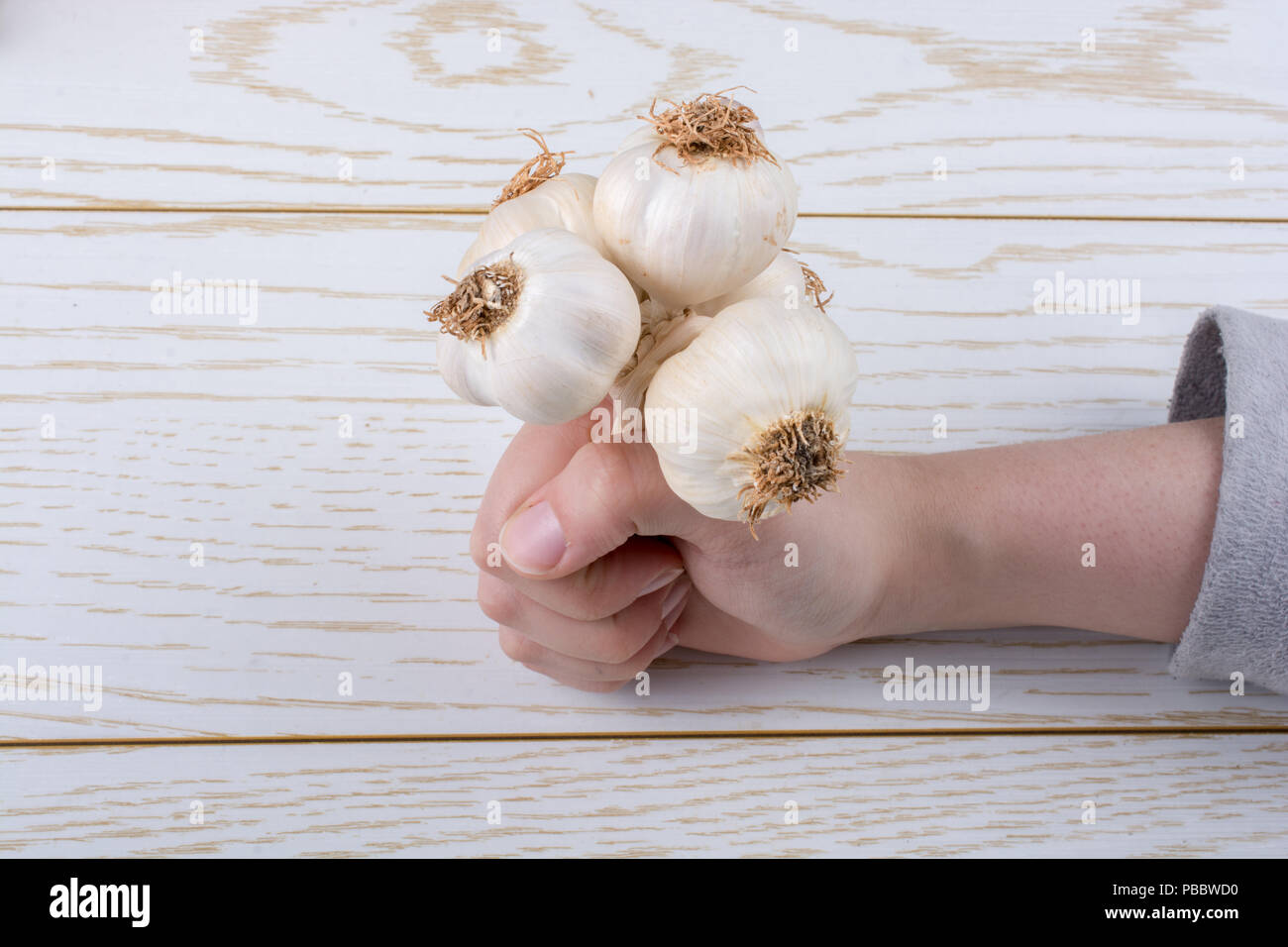 Hand holding cloves of garlic on a wooden texture Stock Photo - Alamy