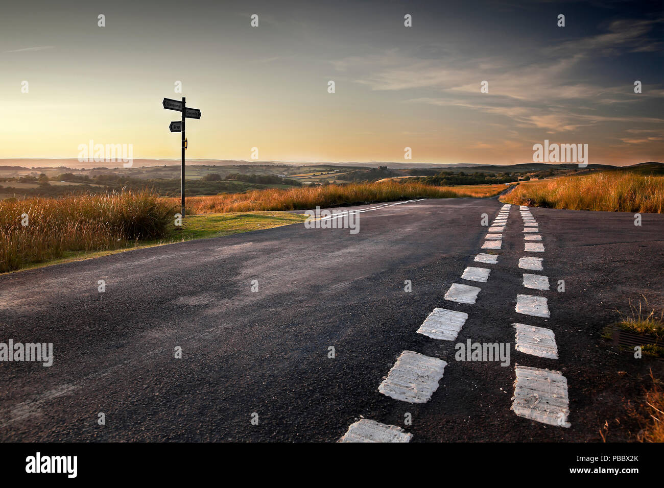 Country road junction and signpost in warm late afternoon light with ...
