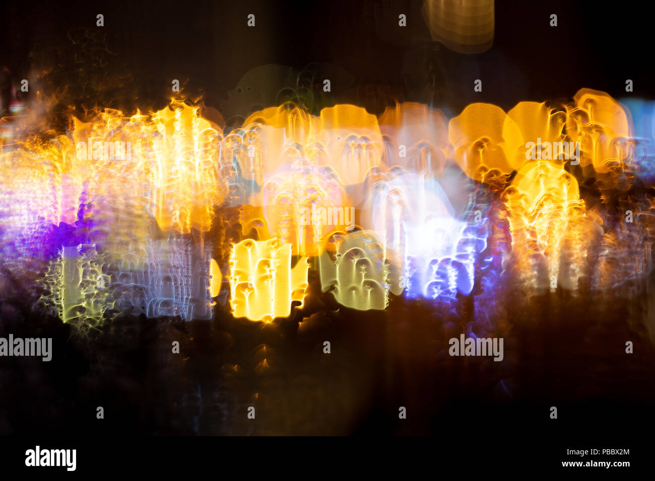Drops of night rain on window, on back plan washed away lights of the ...