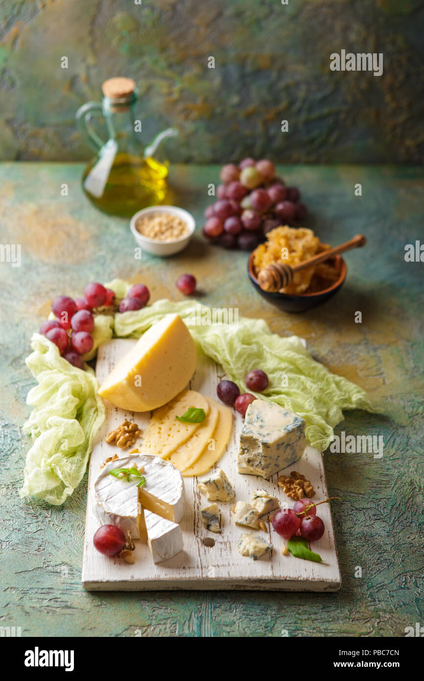 Different types of cheese, red grapes, honeycomb and nuts on a white ...