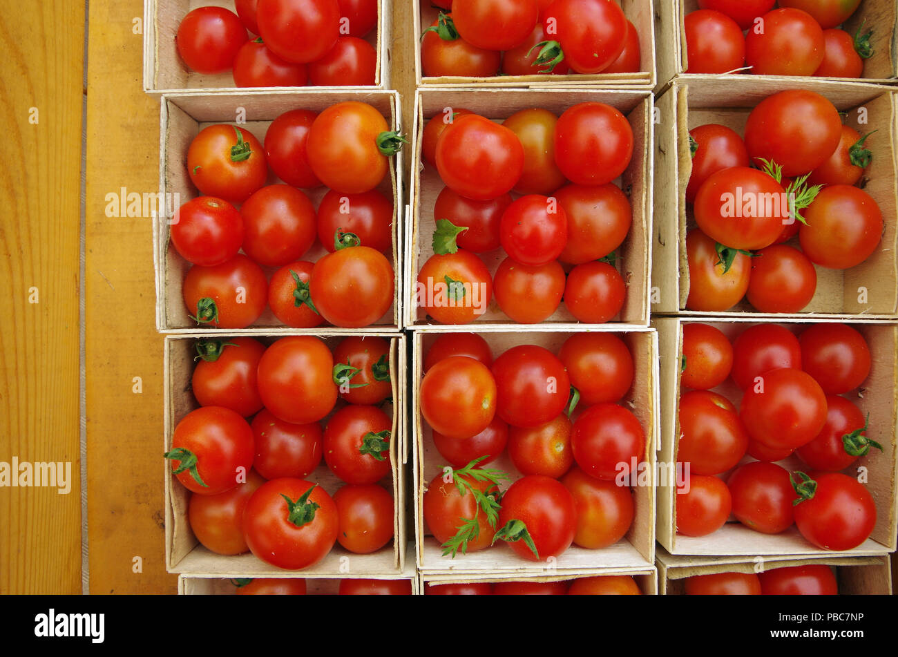 Cherry tomatoes displayed in wooden baskets on wood grain table viewed ...