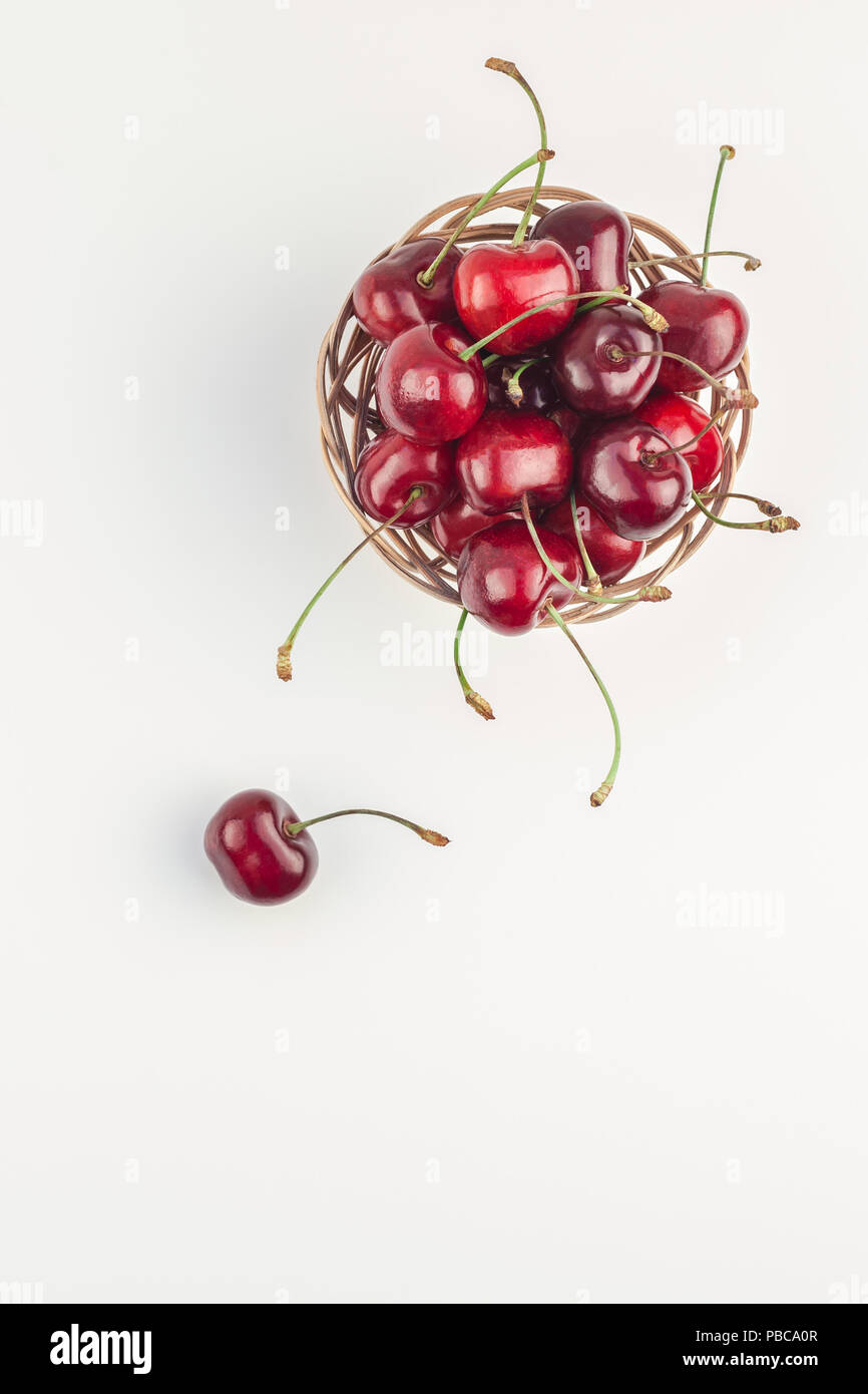 Creative top view of fresh ripe cherry in a small wicker basket with ...