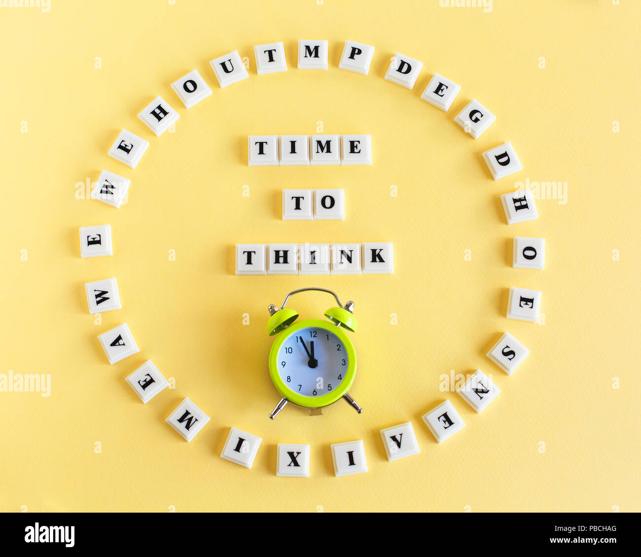 Plastic block cube with word TIME TO THINK and alarm clock on yellow ...
