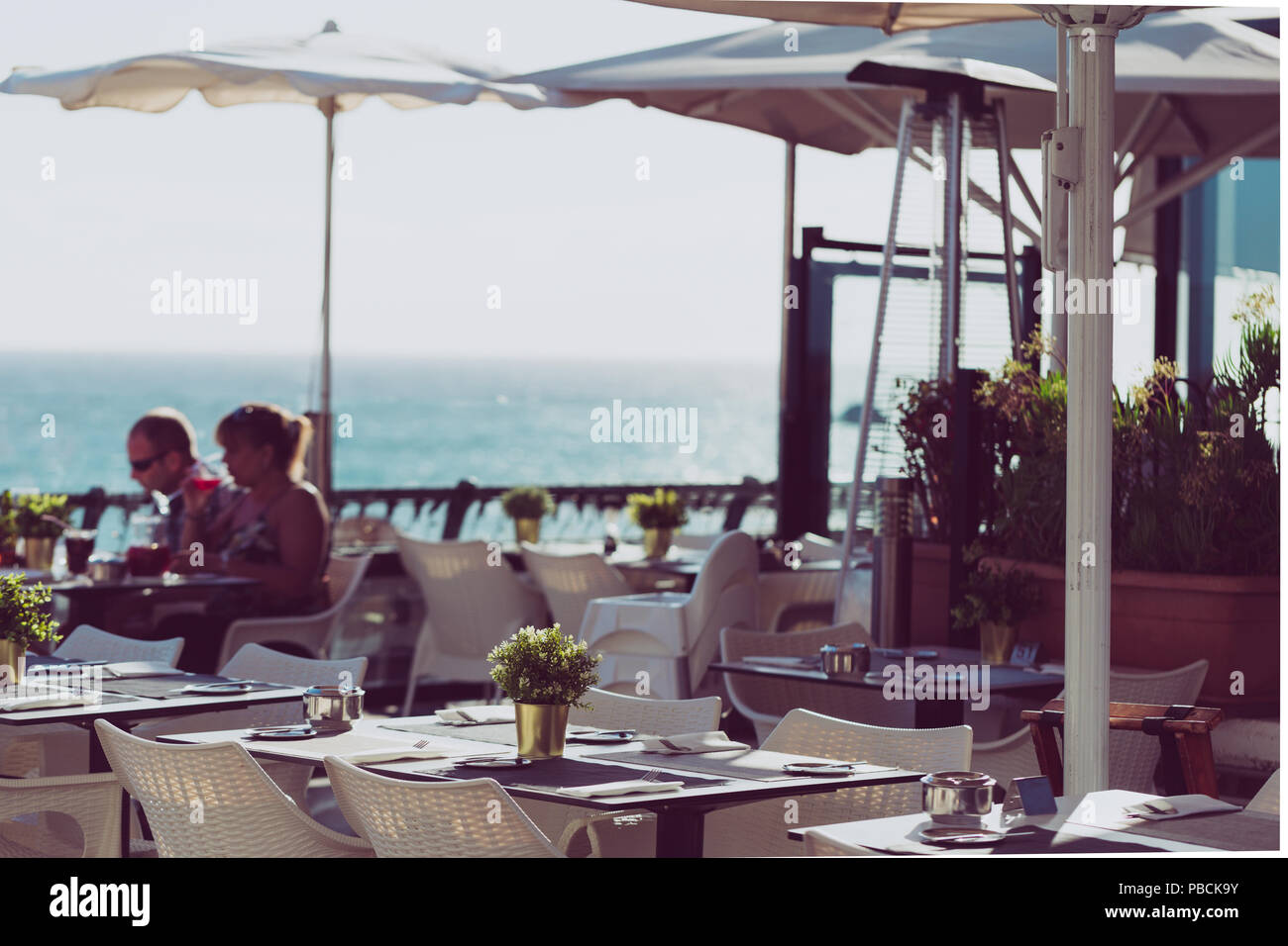 Tables in restaurant on sea coast with couple eating dinner at ...