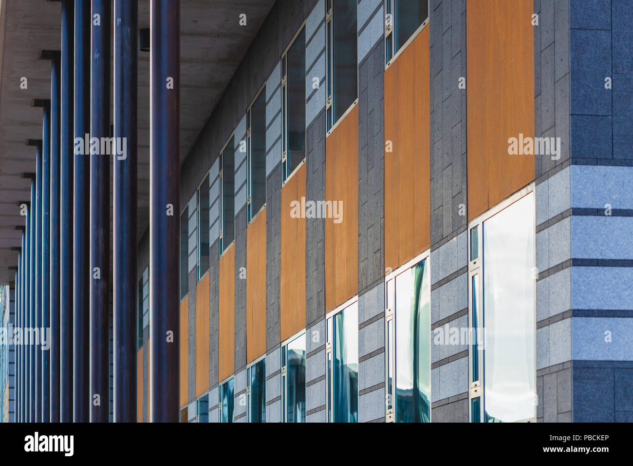 Facade of offices building, repeating windows, steel poles and wooden ...