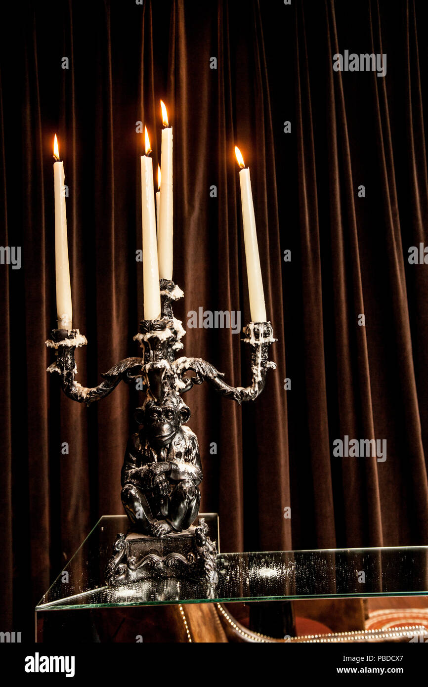 silver candle holder with candles lit on a table. brown background ...