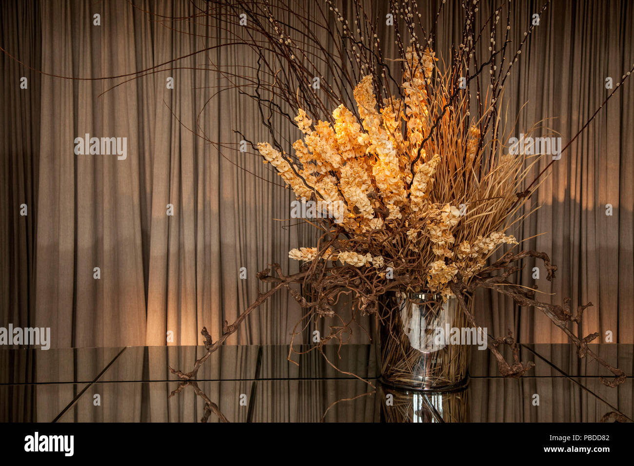 Fancy glass vase with dried flowers on top of a mirror table. brown ...