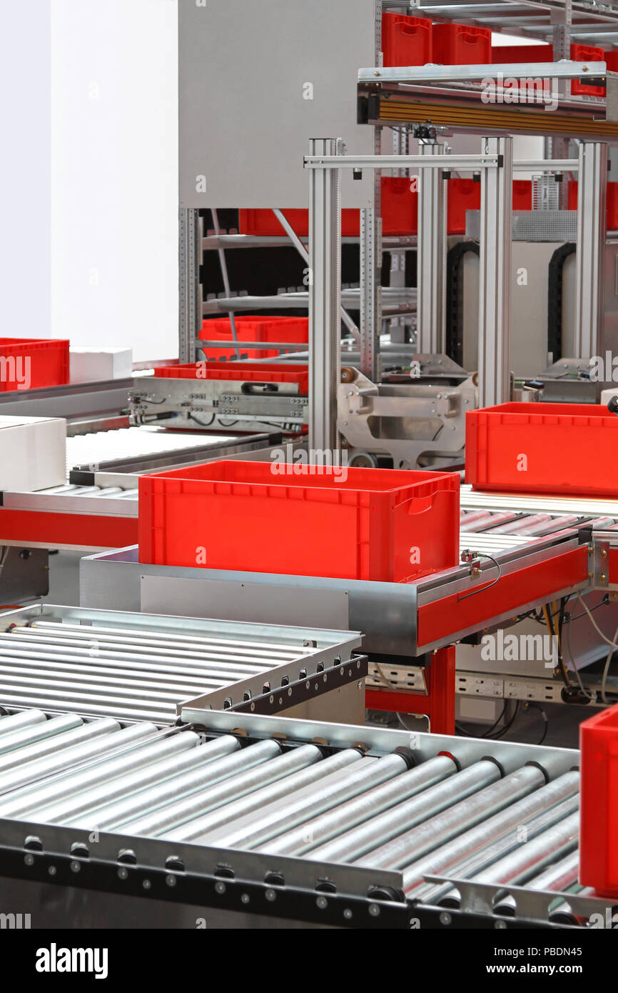 Red crates at conveyor rollers in distribution warehouse Stock Photo ...