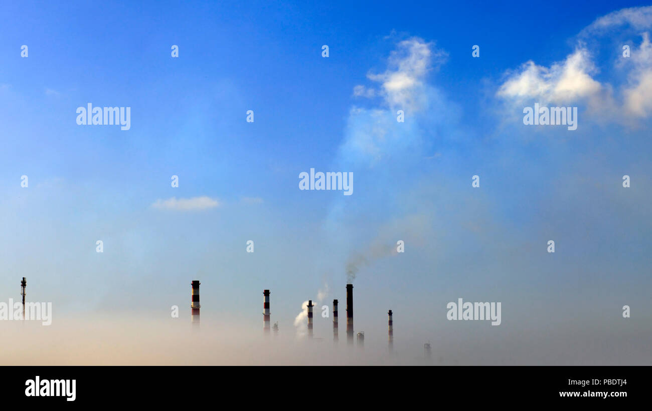 Chimneys of an oil refinery semi losted in smog Stock Photo - Alamy