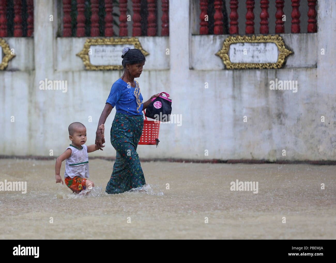 Bago, Myanmar. 28th July, 2018. Residents wade through flood water in ...