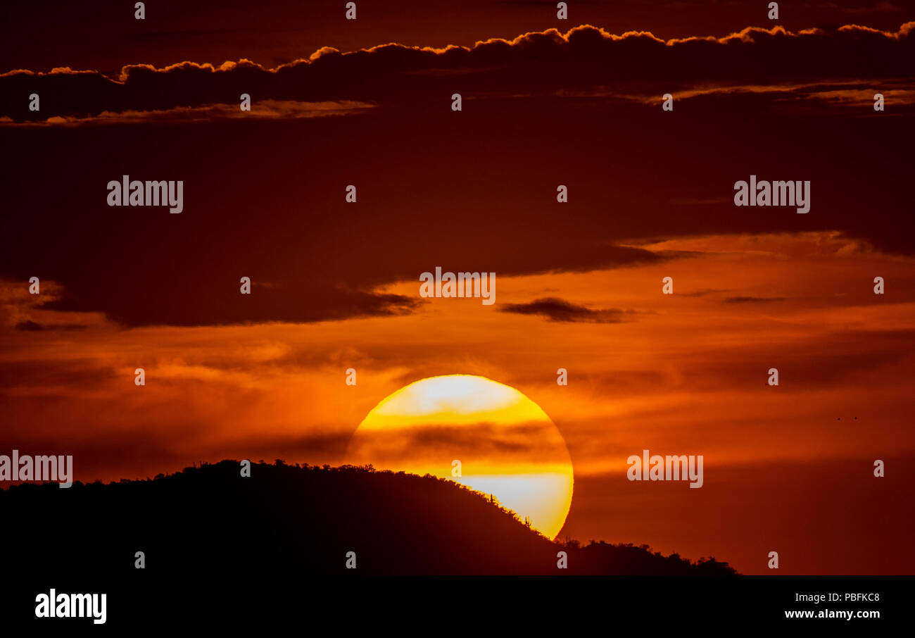 Detail of the sun hiding behind the hill of a hill and the clouds ...