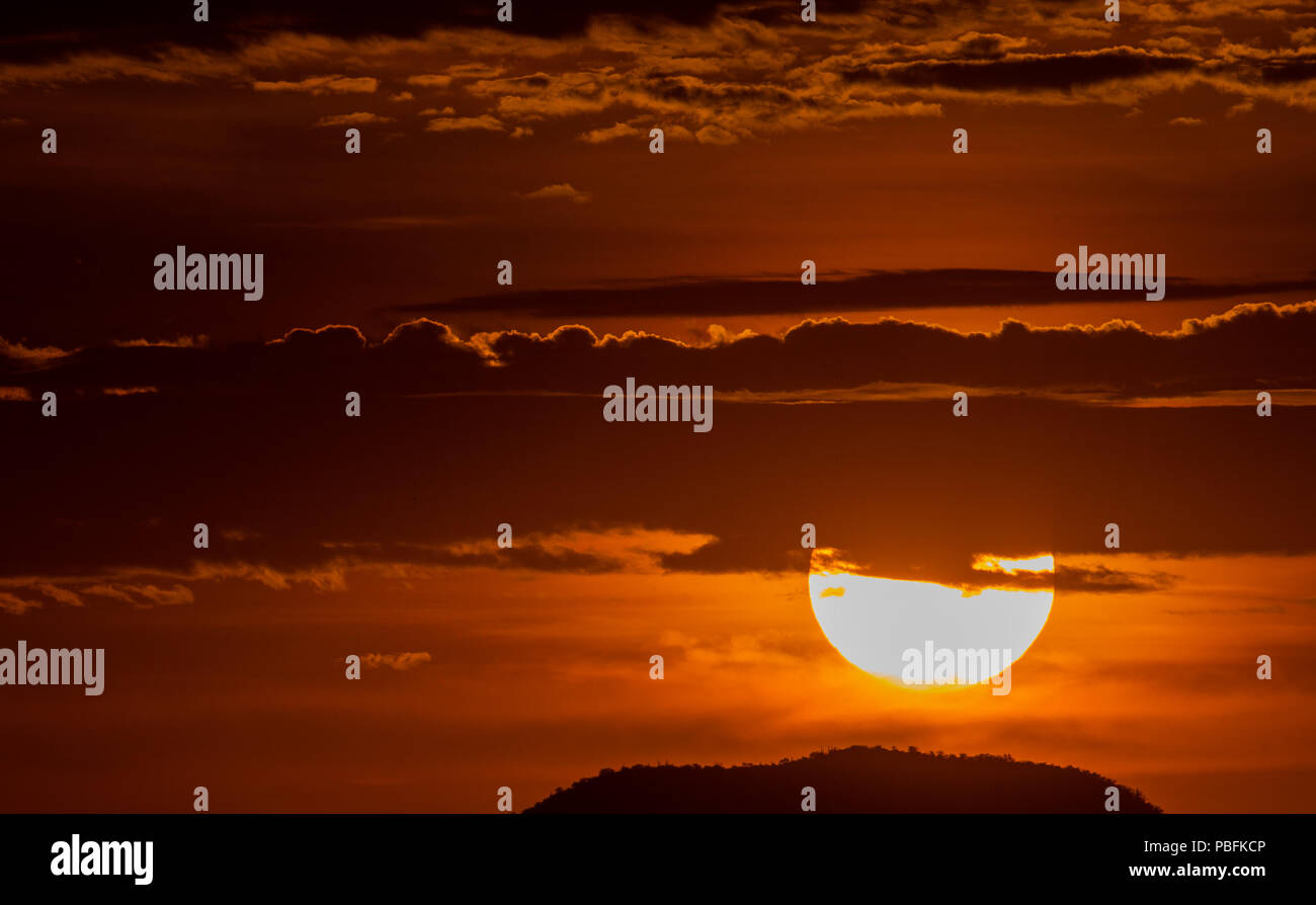 Detail of the sun hiding behind the hill of a hill and the clouds ...