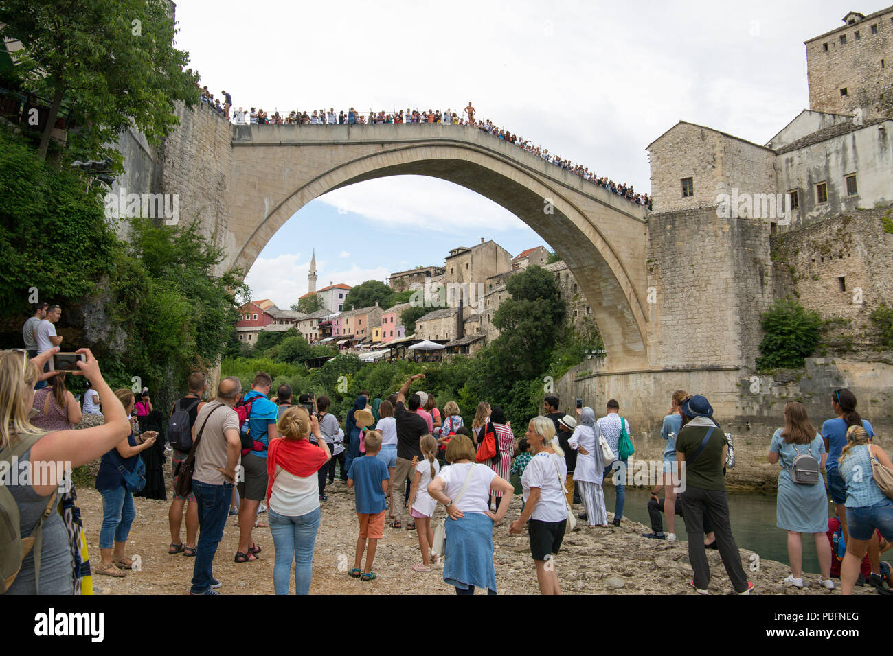 Tourists taking photographs of man about to dove from Mostar bridge ...
