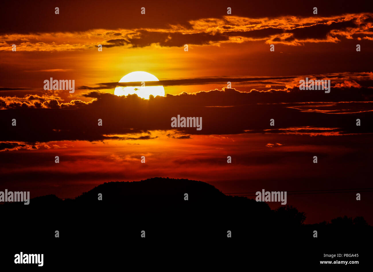 Detail of the sun hiding behind the hill of a hill and the clouds ...