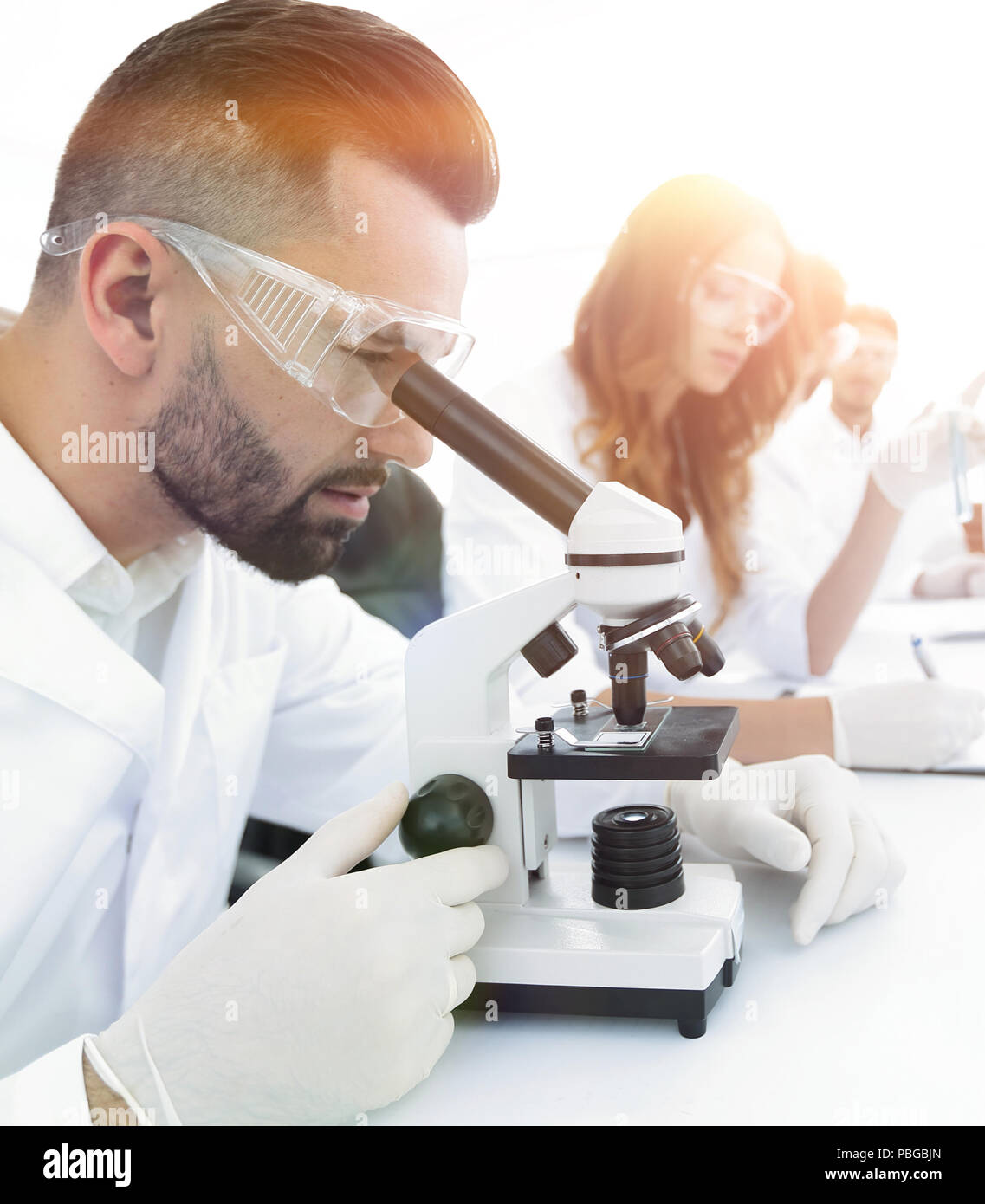 male lab technician looks at the sample under a microscope Stock Photo ...
