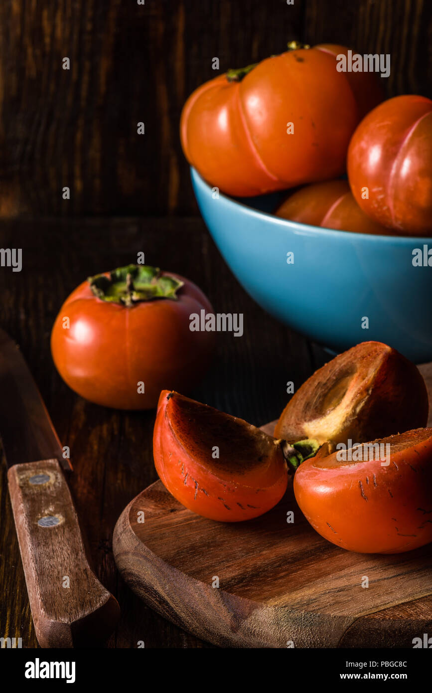 Sliced Persimmon for Three with Knife and Some Fruits in Blue Bowl on ...