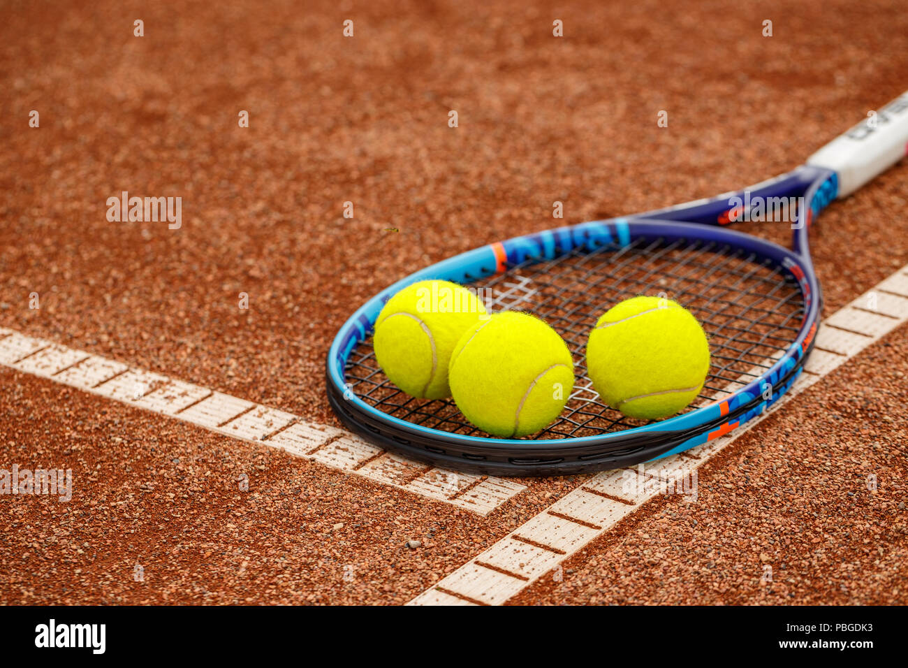Tennis balls and racket on red ground Stock Photo - Alamy
