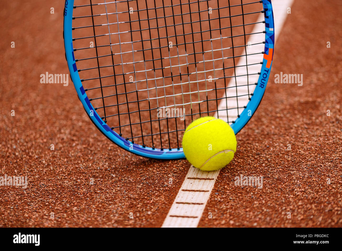 Tennis ball and racket on red ground Stock Photo - Alamy
