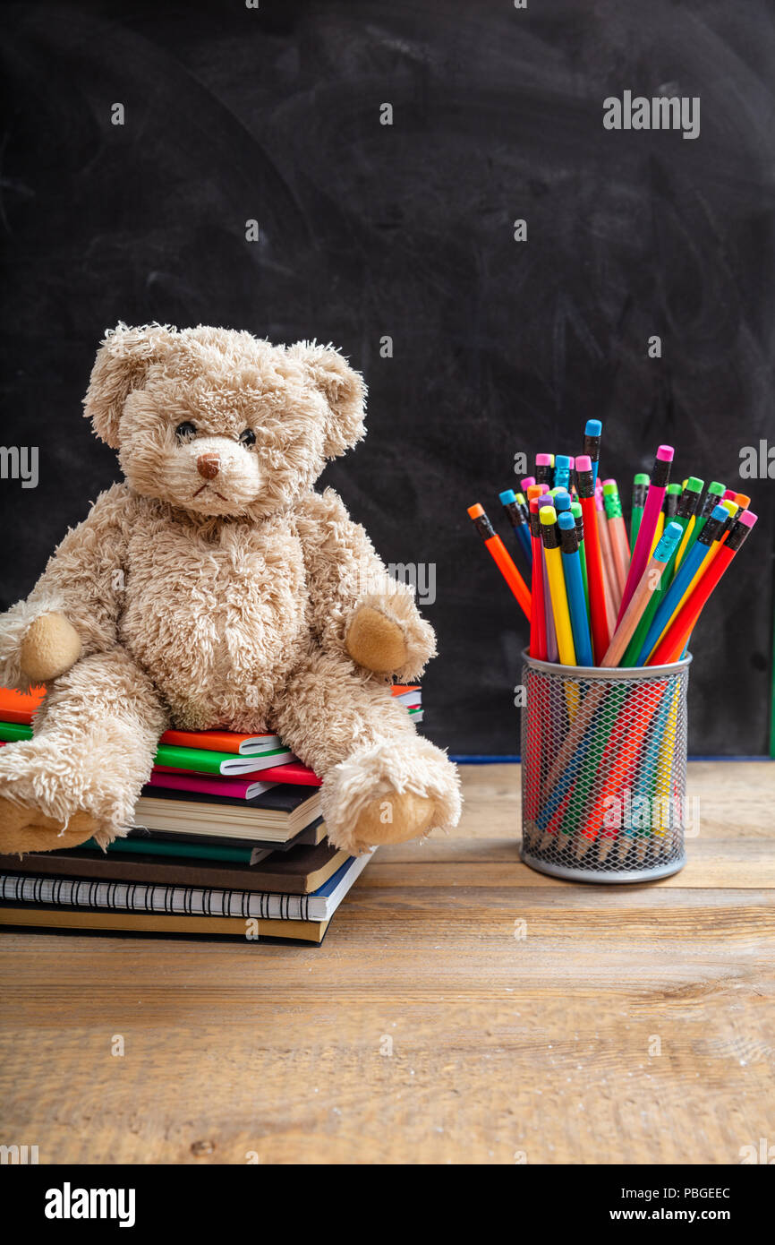 Back to school. Teddy bear and colorful pencils and notebooks on ...