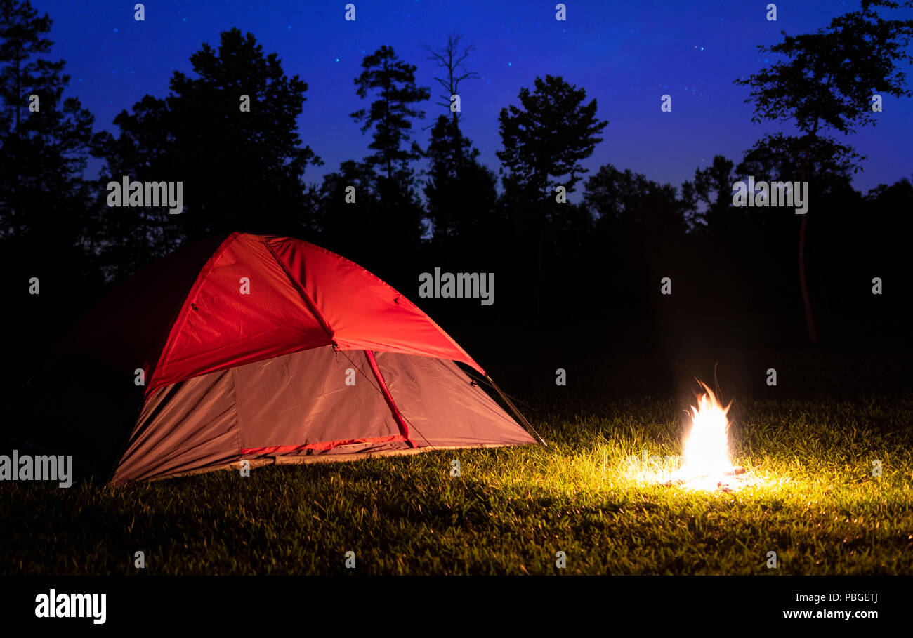 Small campfire lighting up a nylon tent with stars above Stock Photo ...
