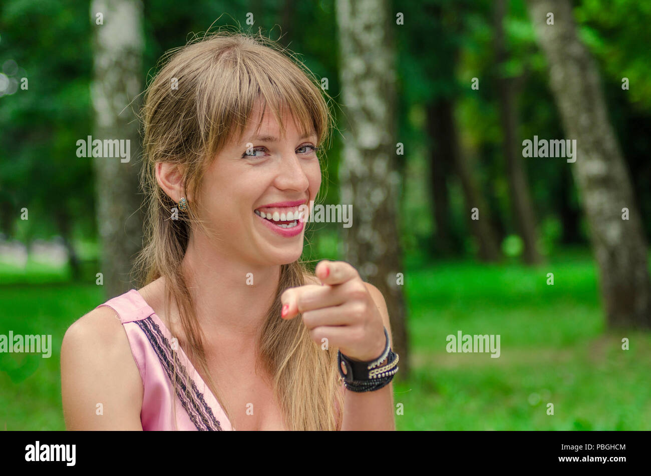 Pointing and laughing. Portrait of young smiling woman pointing finger ...