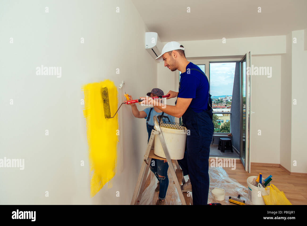 Male and female with paint stick roller and paintbrush coloring their ...
