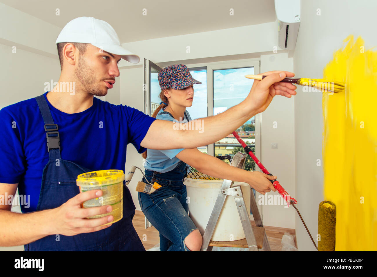 Male and female with paint stick roller and paintbrush coloring their ...