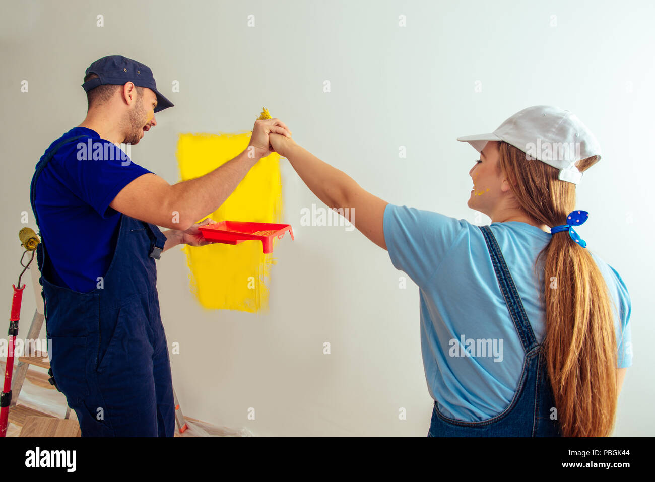 Two people palying with paintbrush and having fun while coloring walls ...