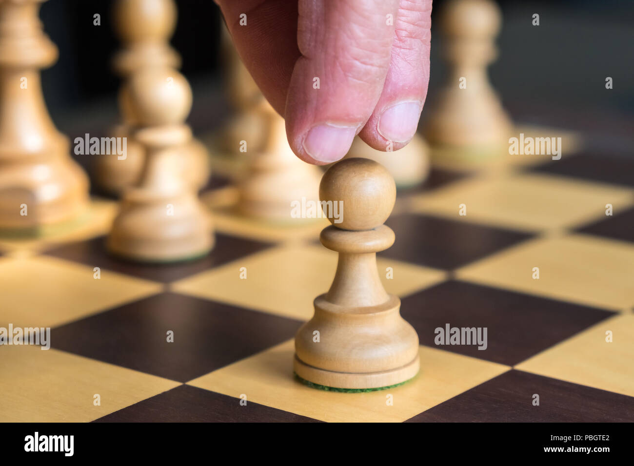 Hand moving a white pawn on a chess board Stock Photo - Alamy