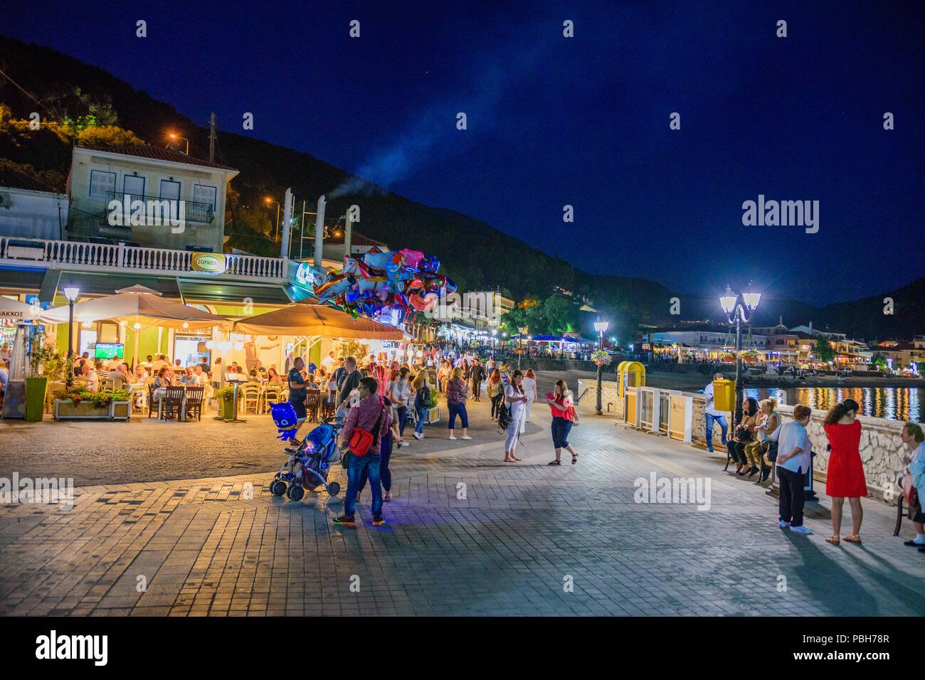 The amazing coastal city of Parga at night. Tourists and visitors walk ...