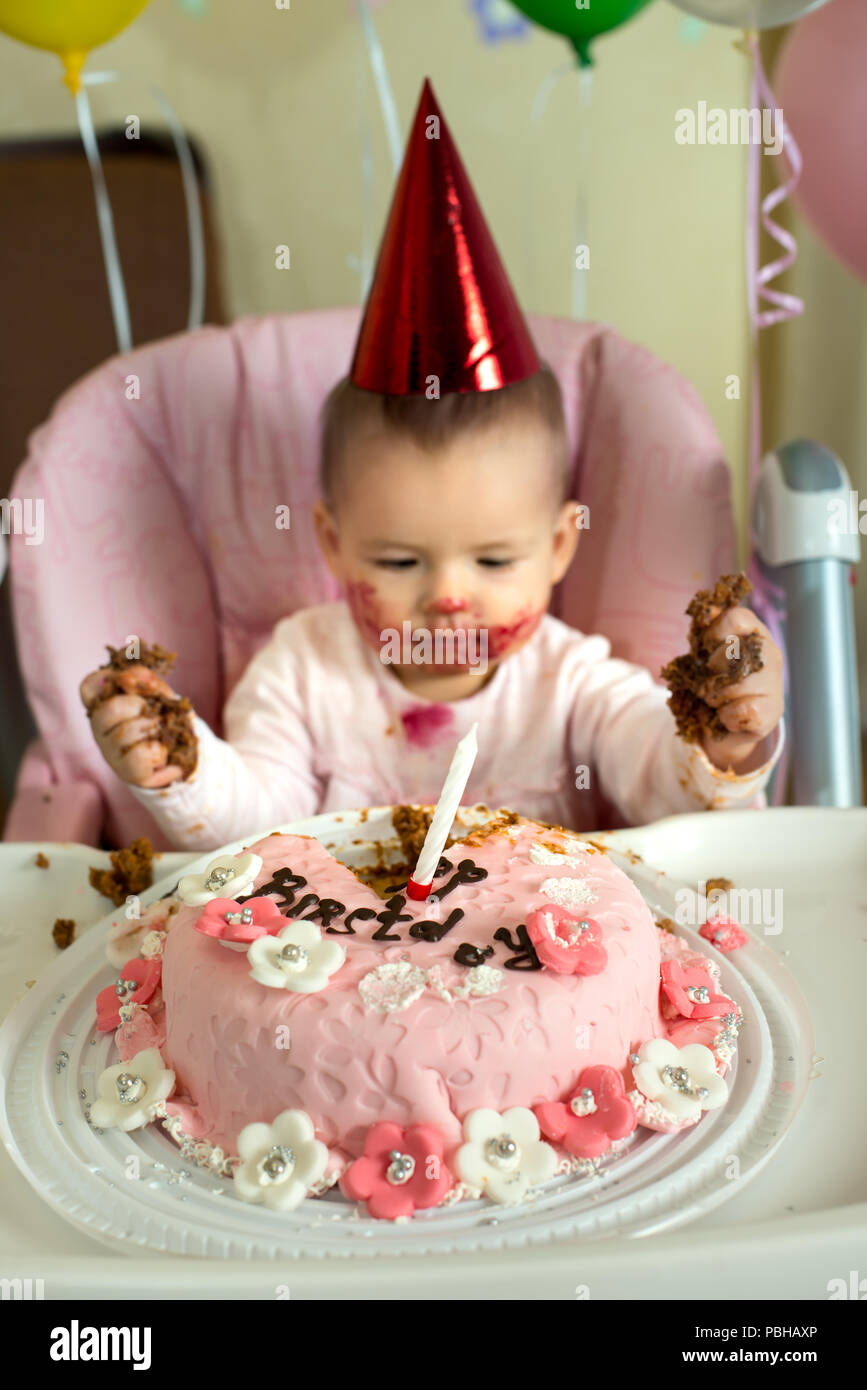 one-year-old little girl solemnize birthday, eating cake, vertical ...
