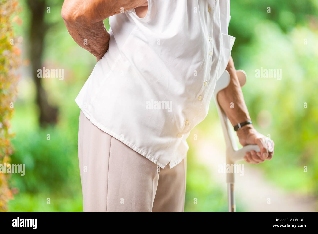 Elderly woman outdoors with lower back pain Stock Photo - Alamy
