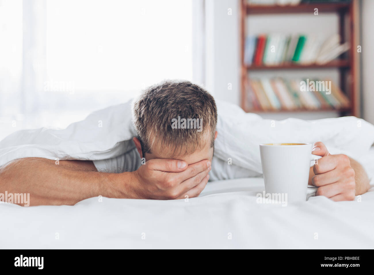 Man trying to wake up in the morning after night out Stock Photo - Alamy