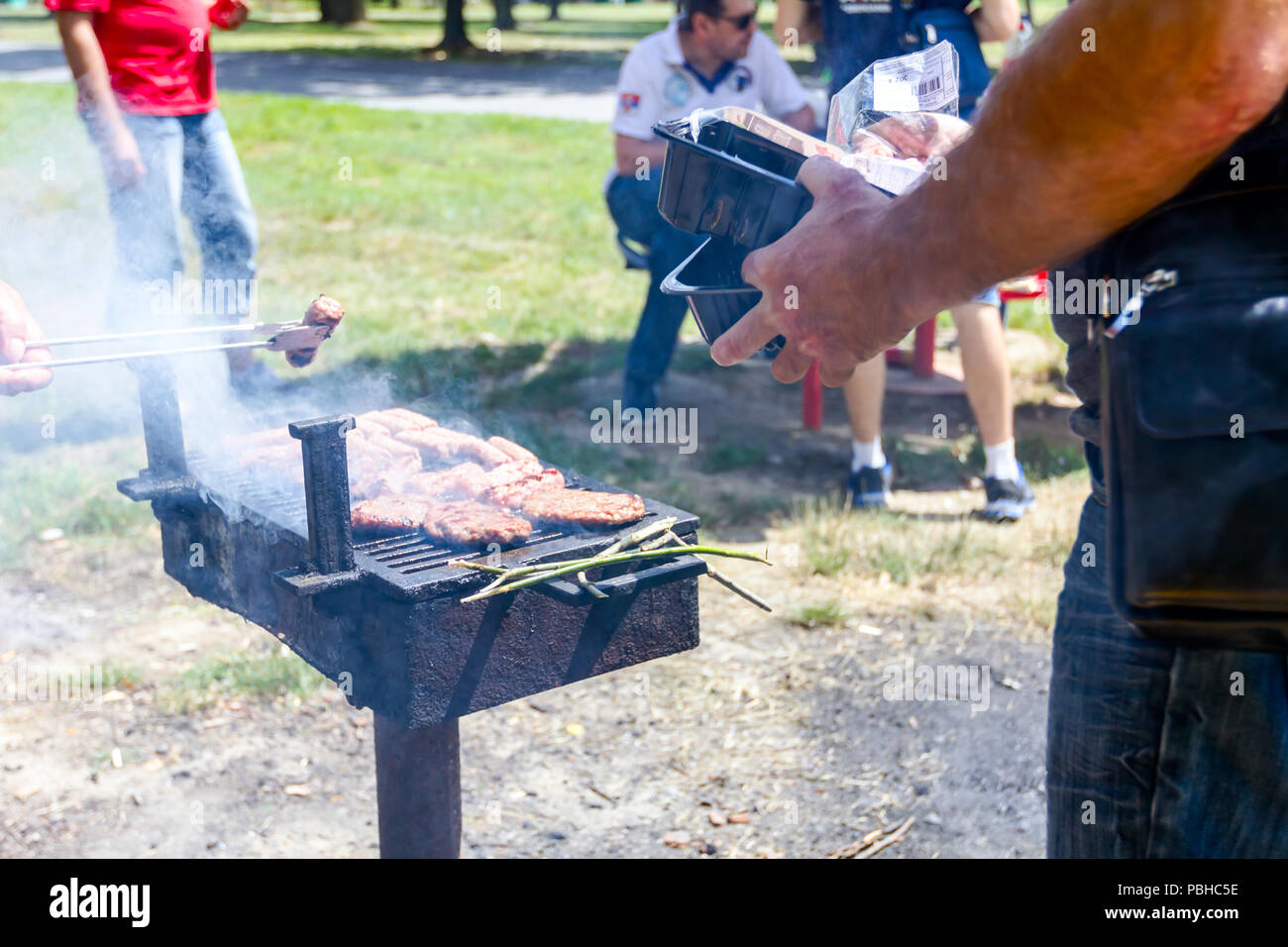 Man take out roasted kebabs with metal tongs, removes them from ...