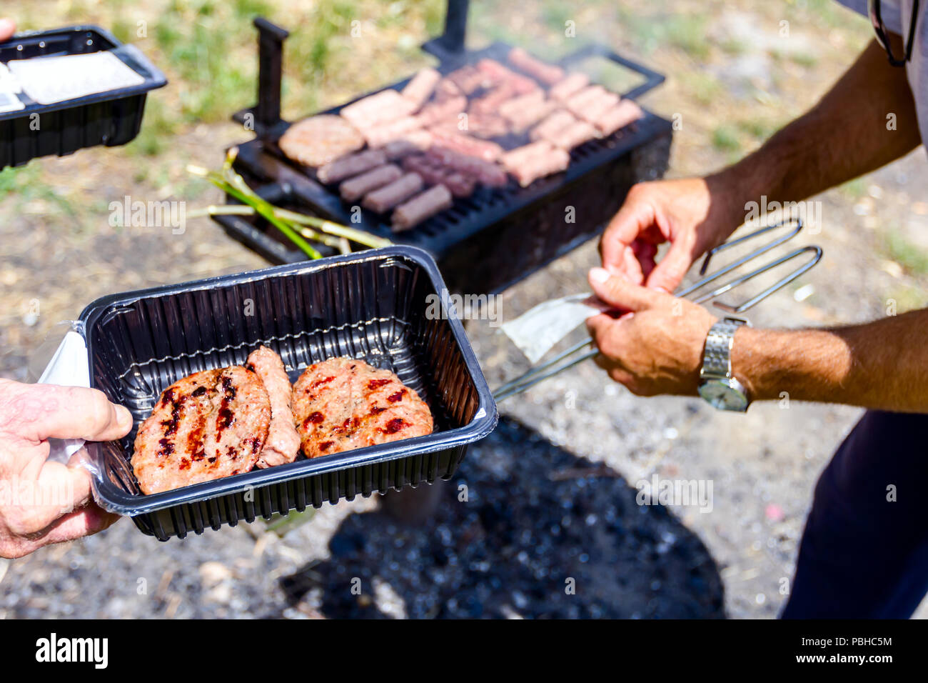 Man take out roasted kebabs with metal tongs, removes them from ...
