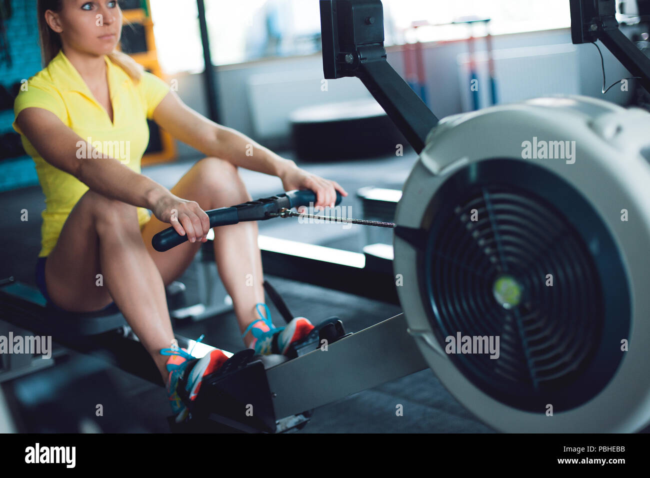 Rowing in the gym. Young woman training using a rowing machine Stock ...