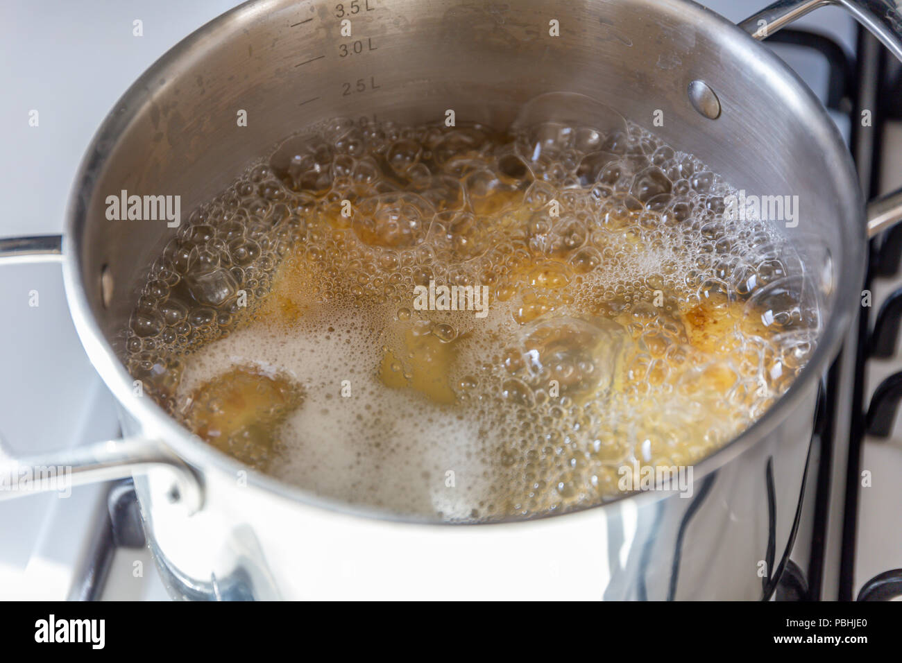 Pan of potatoes cooking in boiling water Stock Photo - Alamy