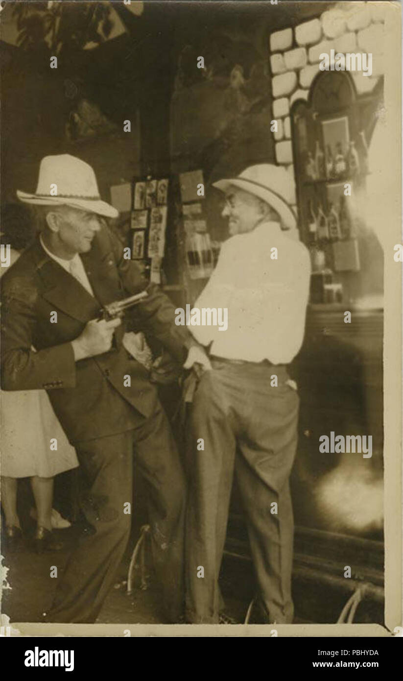 1781 Two men, joking around with a gun, standing in a place that sells ...
