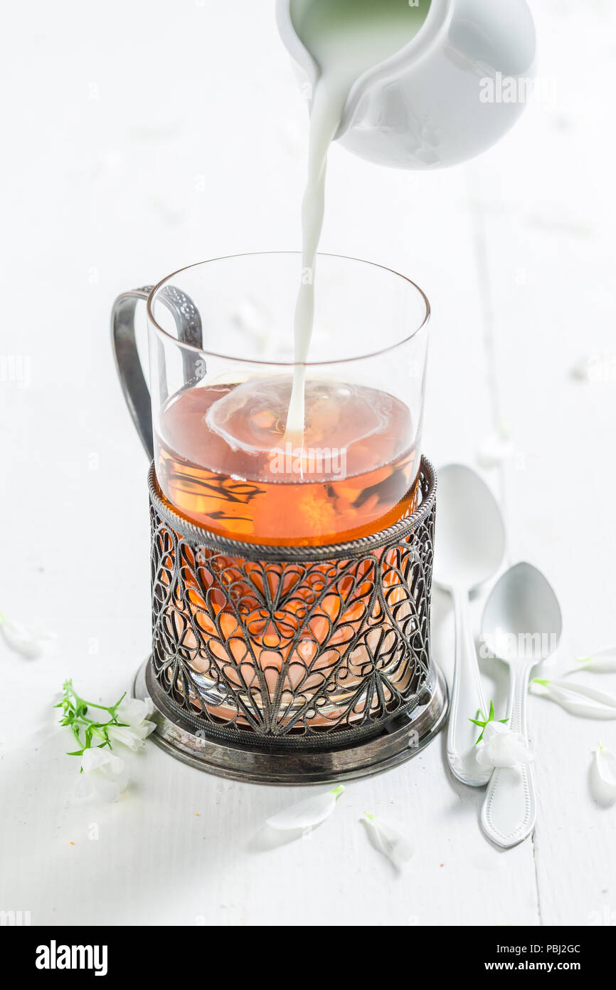 Pouring milk into tea on white background Stock Photo - Alamy